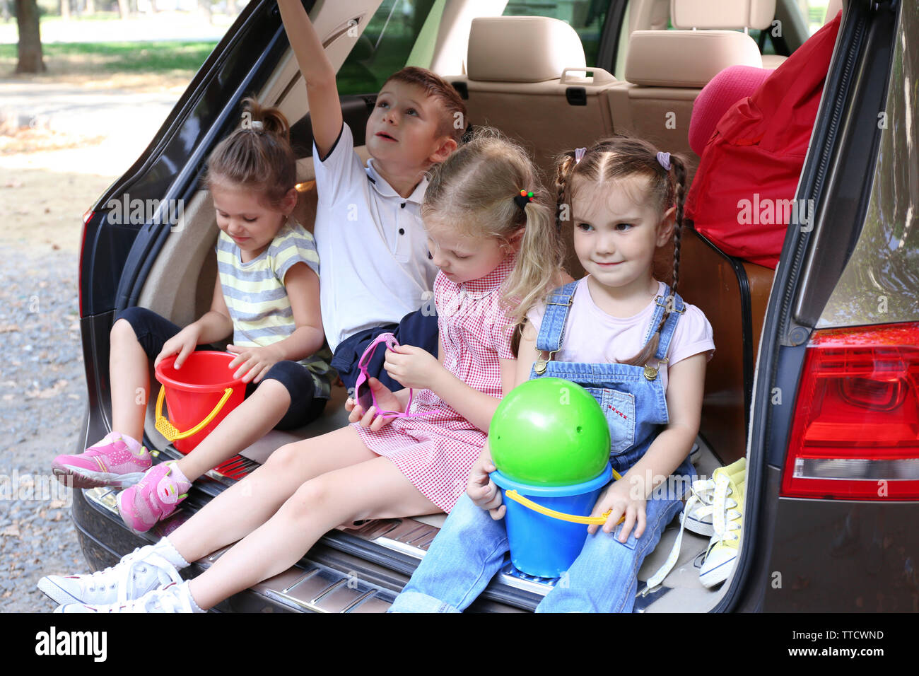 Three beautiful girls and boy sit on a car trunk and laughing Stock ...