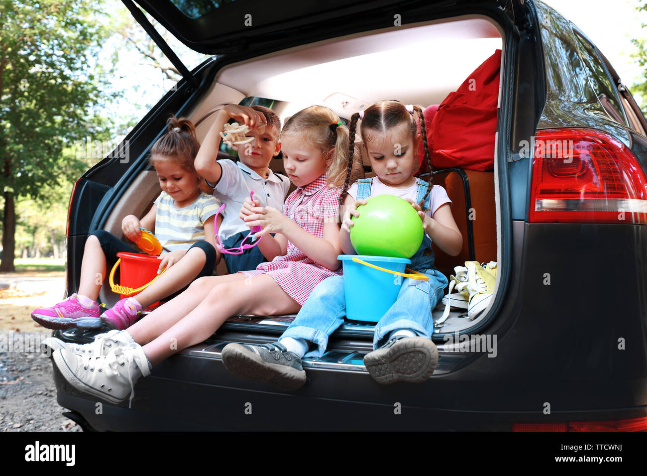 Three beautiful girls and boy sit on a car trunk and laughing Stock ...
