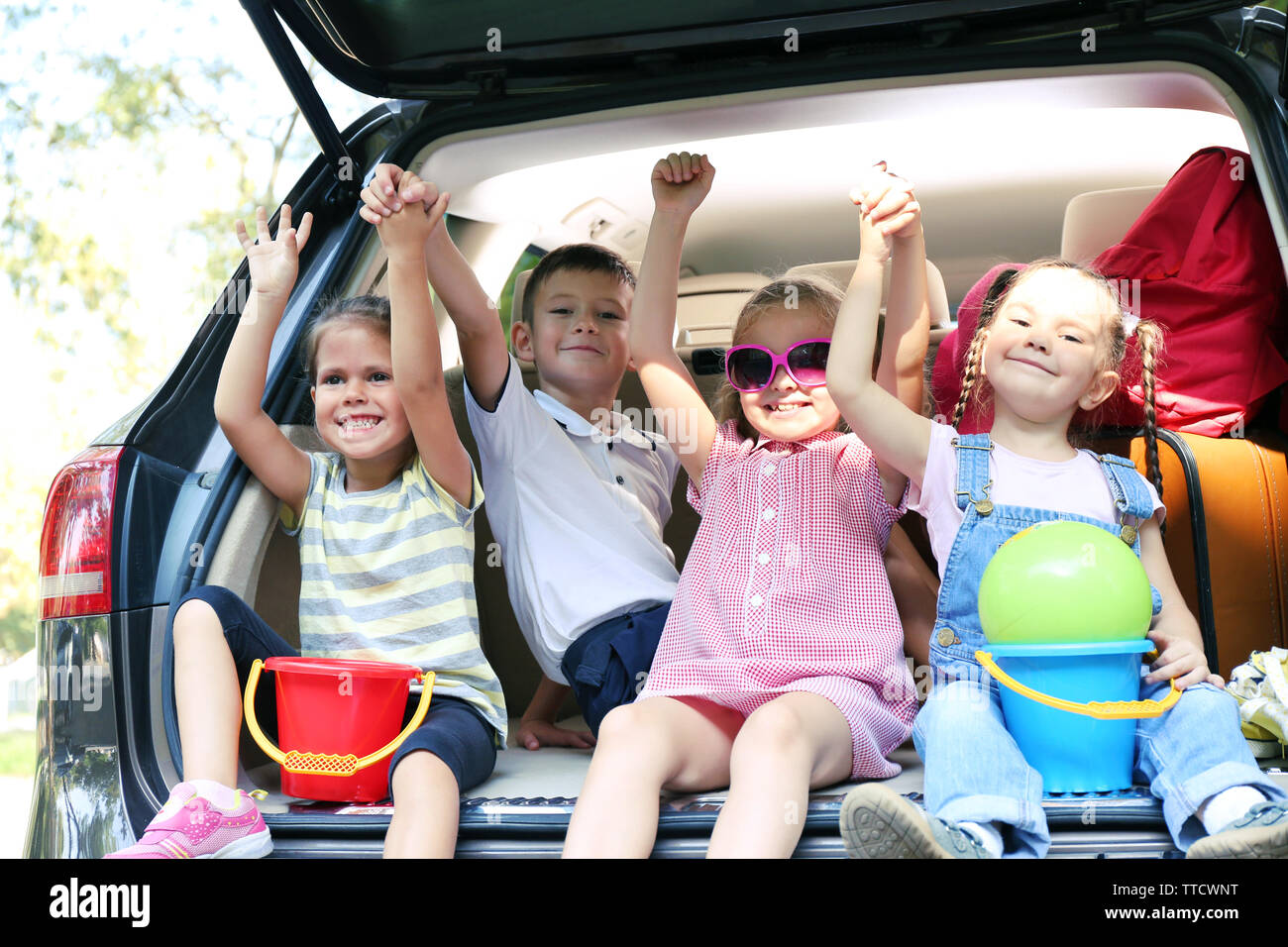 Three adorable girls and boy sit on a car trunk and laughing Stock ...