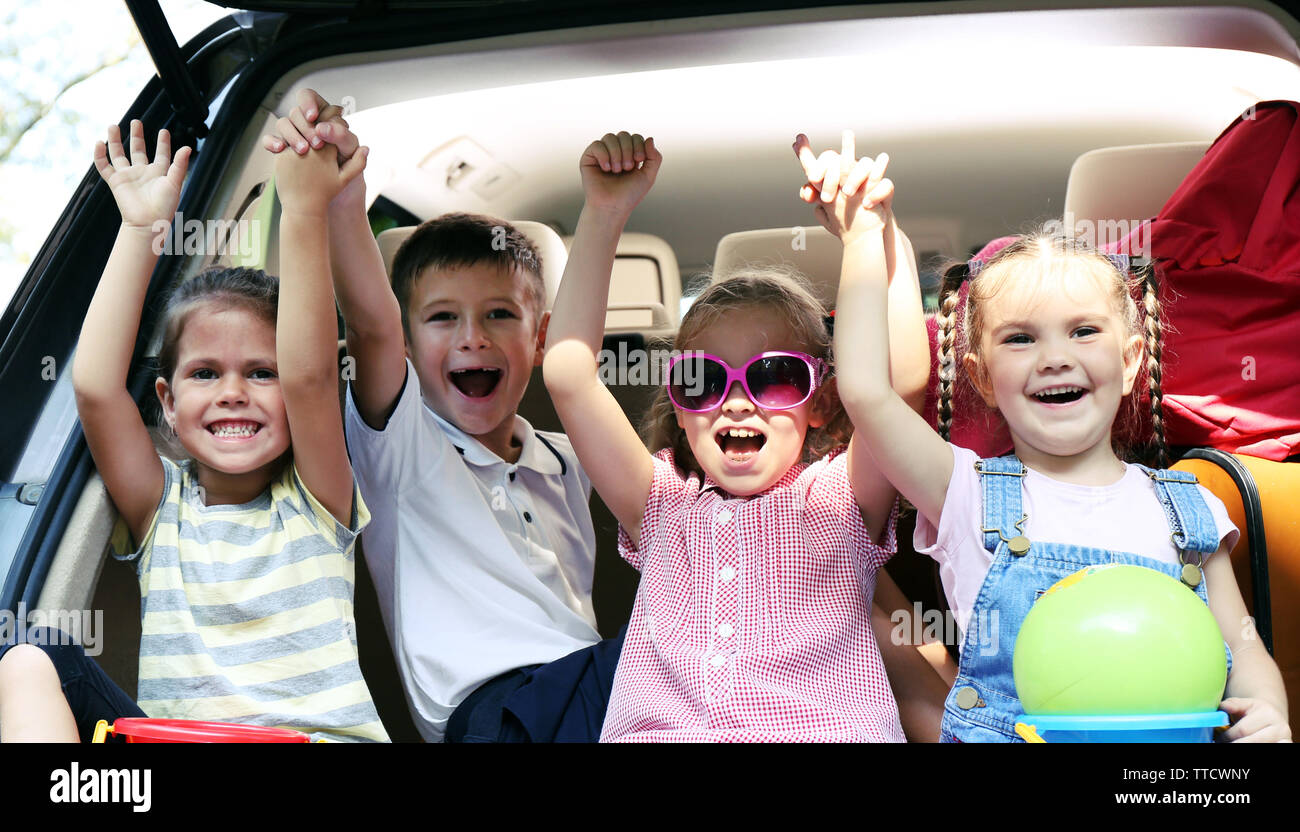 Three adorable girls and boy sit on a car trunk and laughing Stock ...