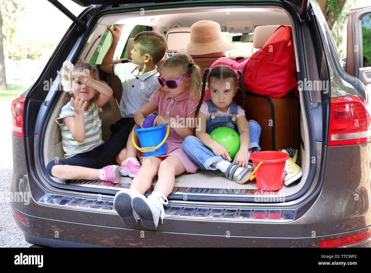 Three beautiful girls and boy sit on a car trunk and laughing Stock ...
