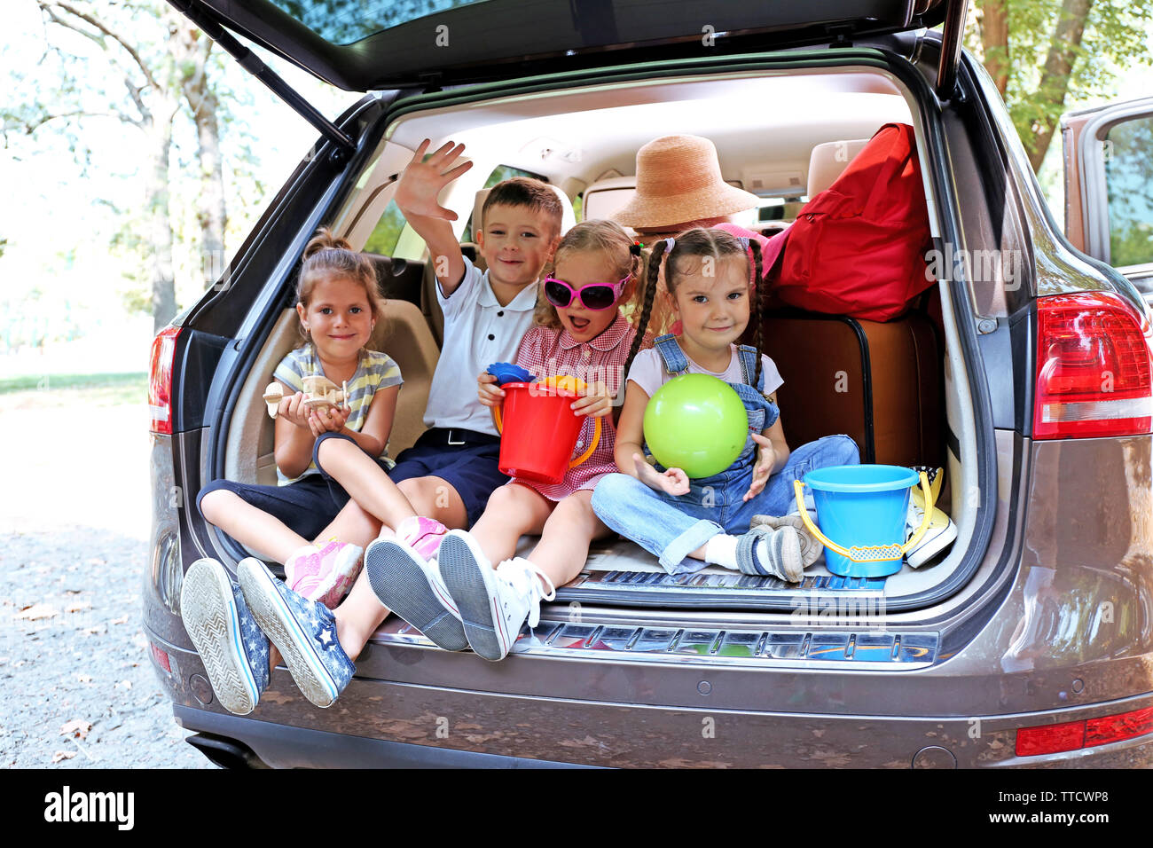 Three beautiful girls and boy sit on a car trunk and laughing Stock ...