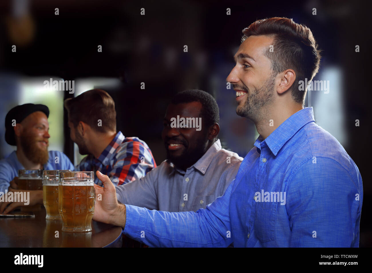Young men drinking beer in pub Stock Photo - Alamy