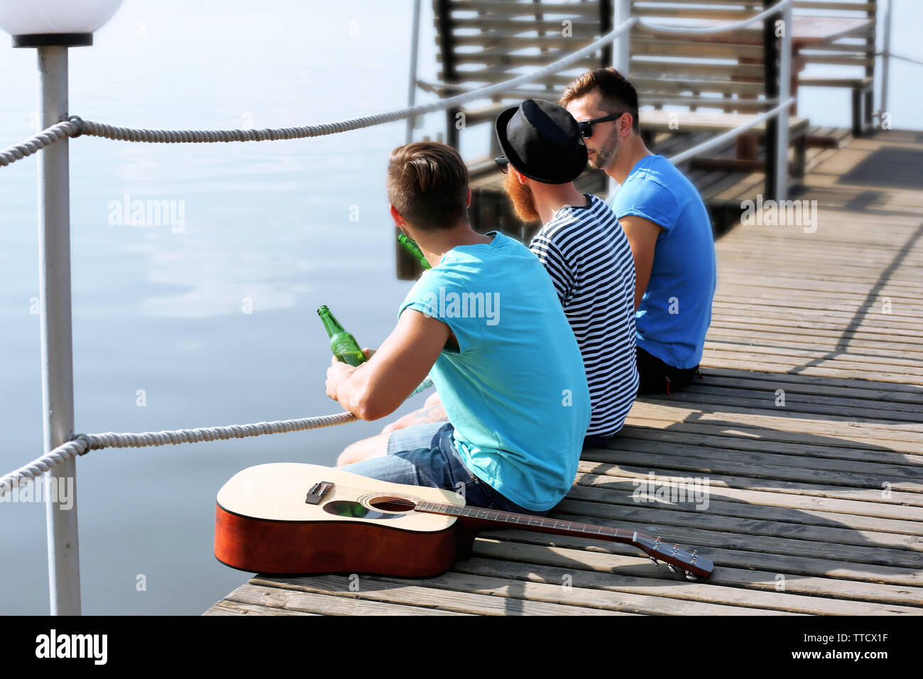 Young men sitting on the dock and talking with each other Stock Photo ...