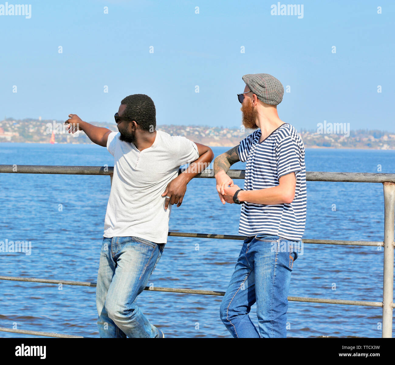 Two young men talking on the riverside Stock Photo - Alamy