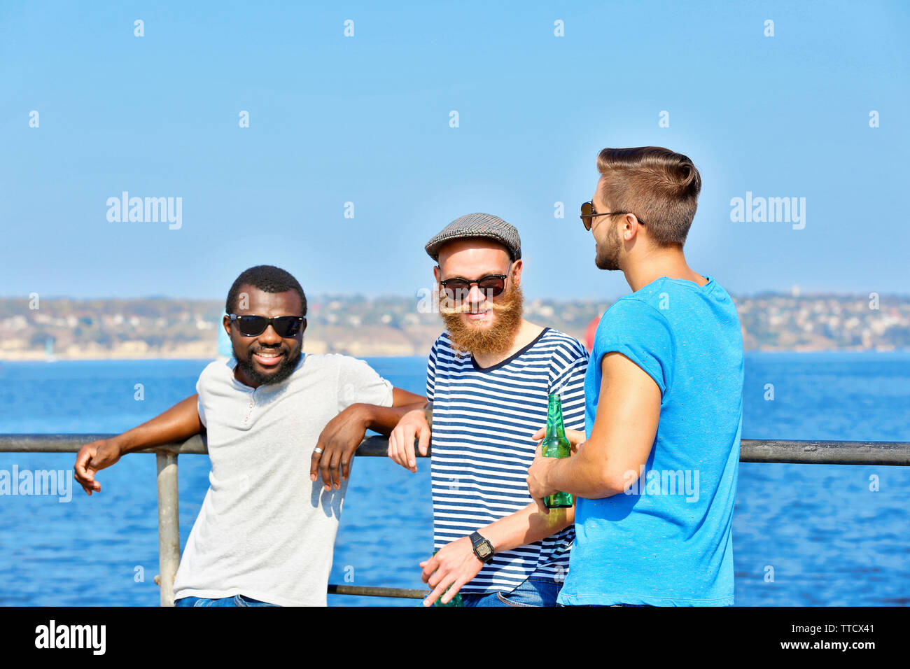 Young men talking on the riverside Stock Photo - Alamy