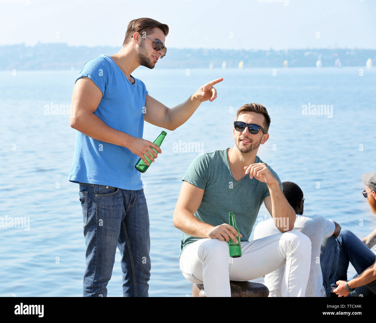 Young men talking on the riverside Stock Photo - Alamy