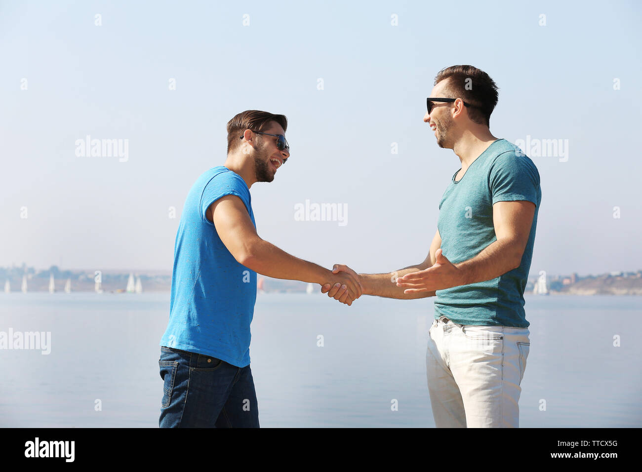 Two young men meeting on the riverside Stock Photo - Alamy