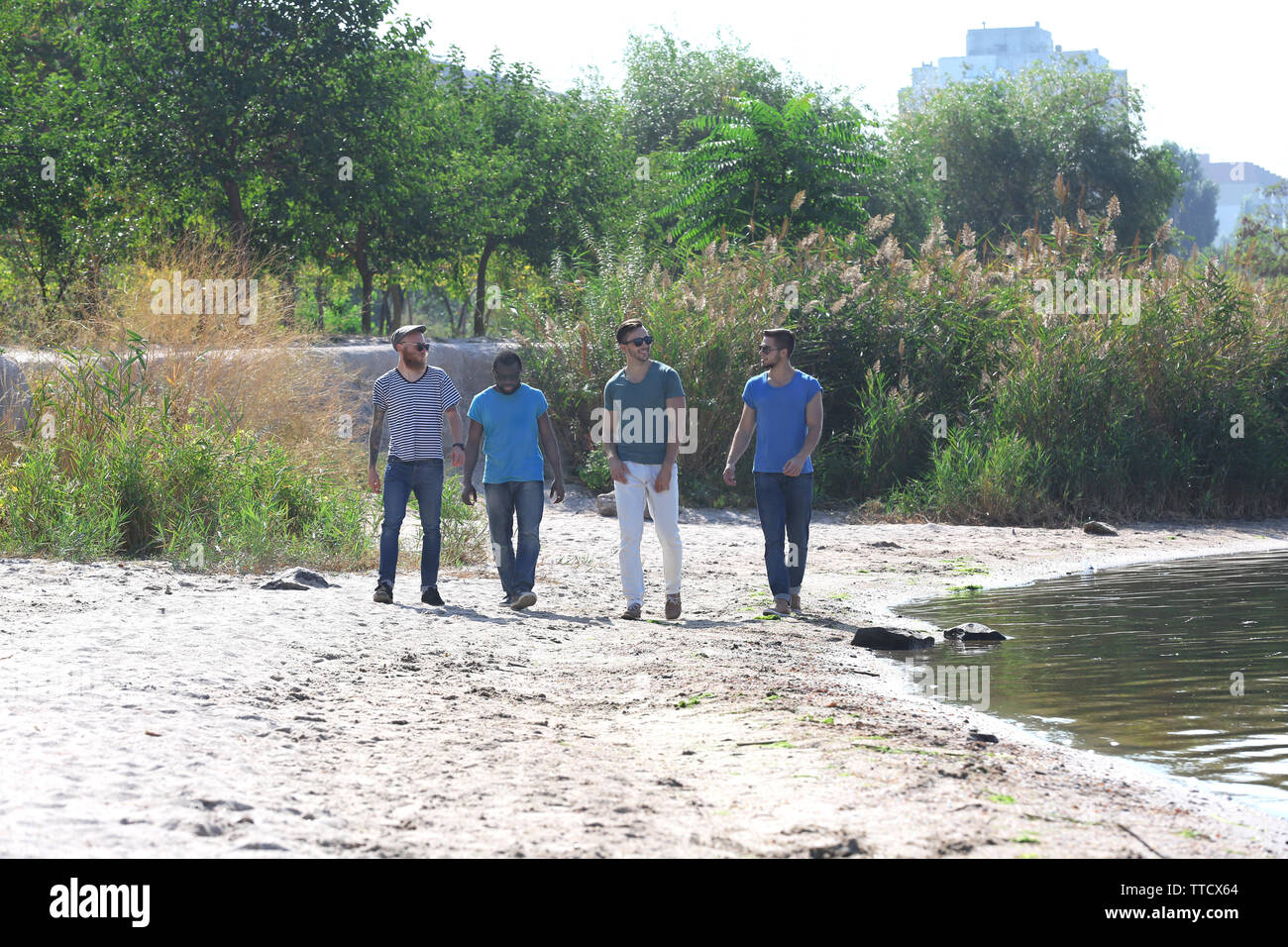 Young men walking along the riverside Stock Photo - Alamy