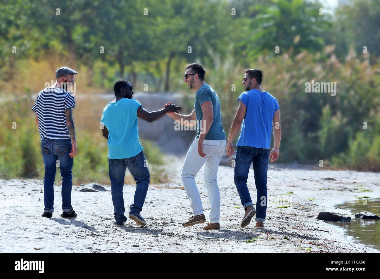 Young men walking along the riverside Stock Photo - Alamy