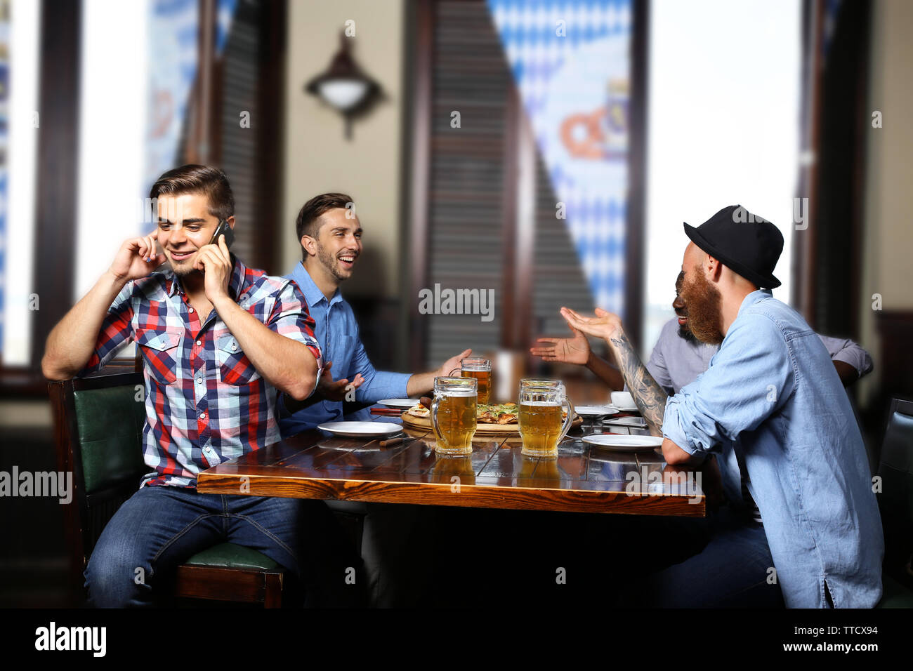 Young men drinking beer and talking in cafe Stock Photo - Alamy