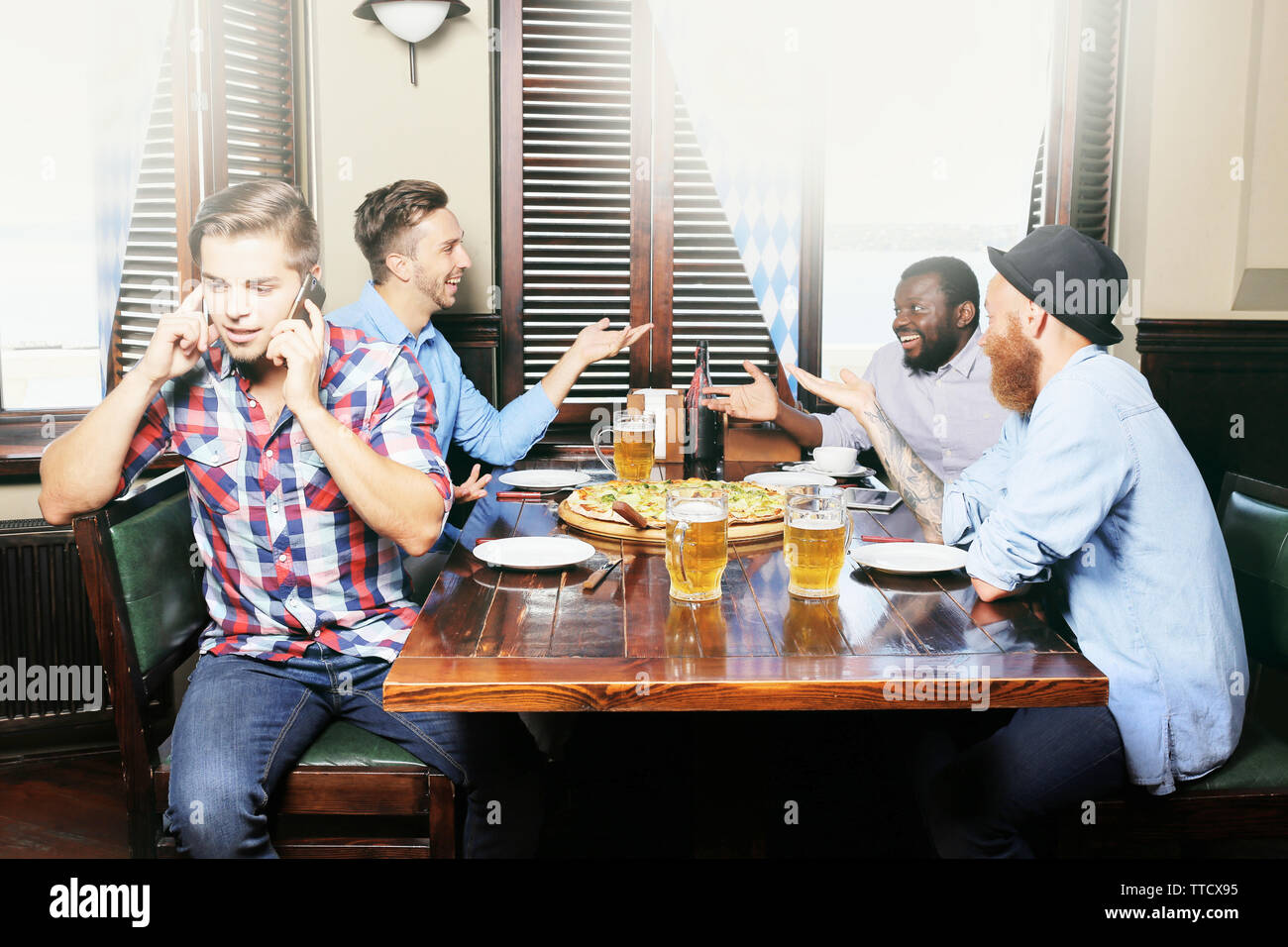 Young men drinking beer and talking in cafe Stock Photo - Alamy