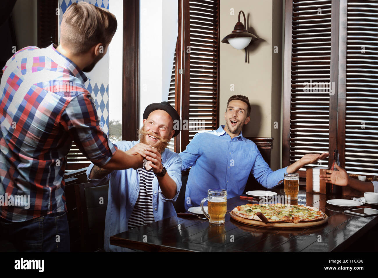 Young men drinking beer and talking in cafe Stock Photo - Alamy