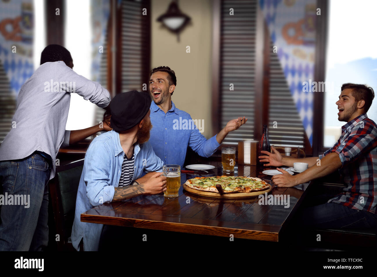 Young men drinking beer and talking in cafe Stock Photo - Alamy