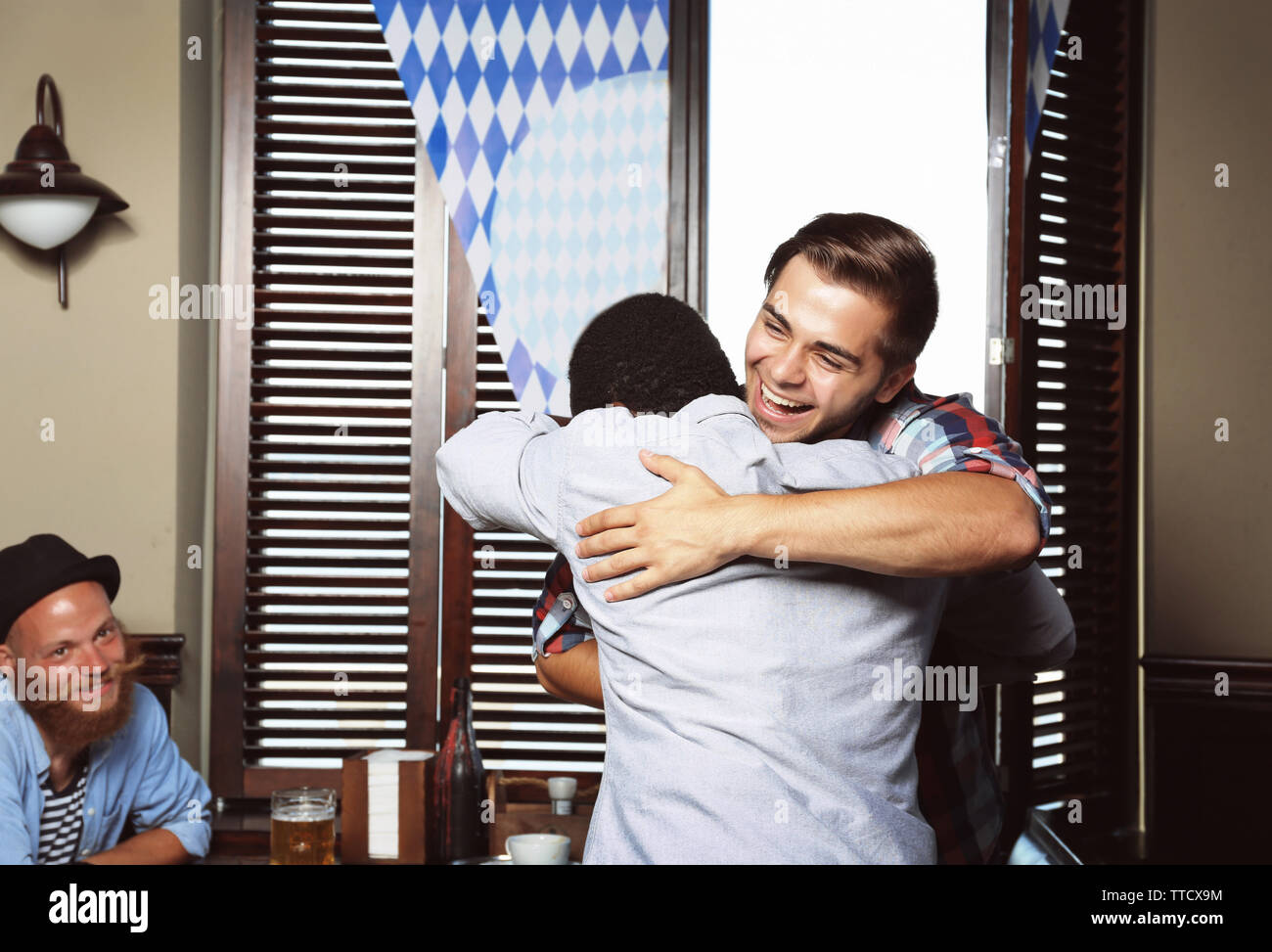 Young men drinking beer and talking in cafe Stock Photo - Alamy