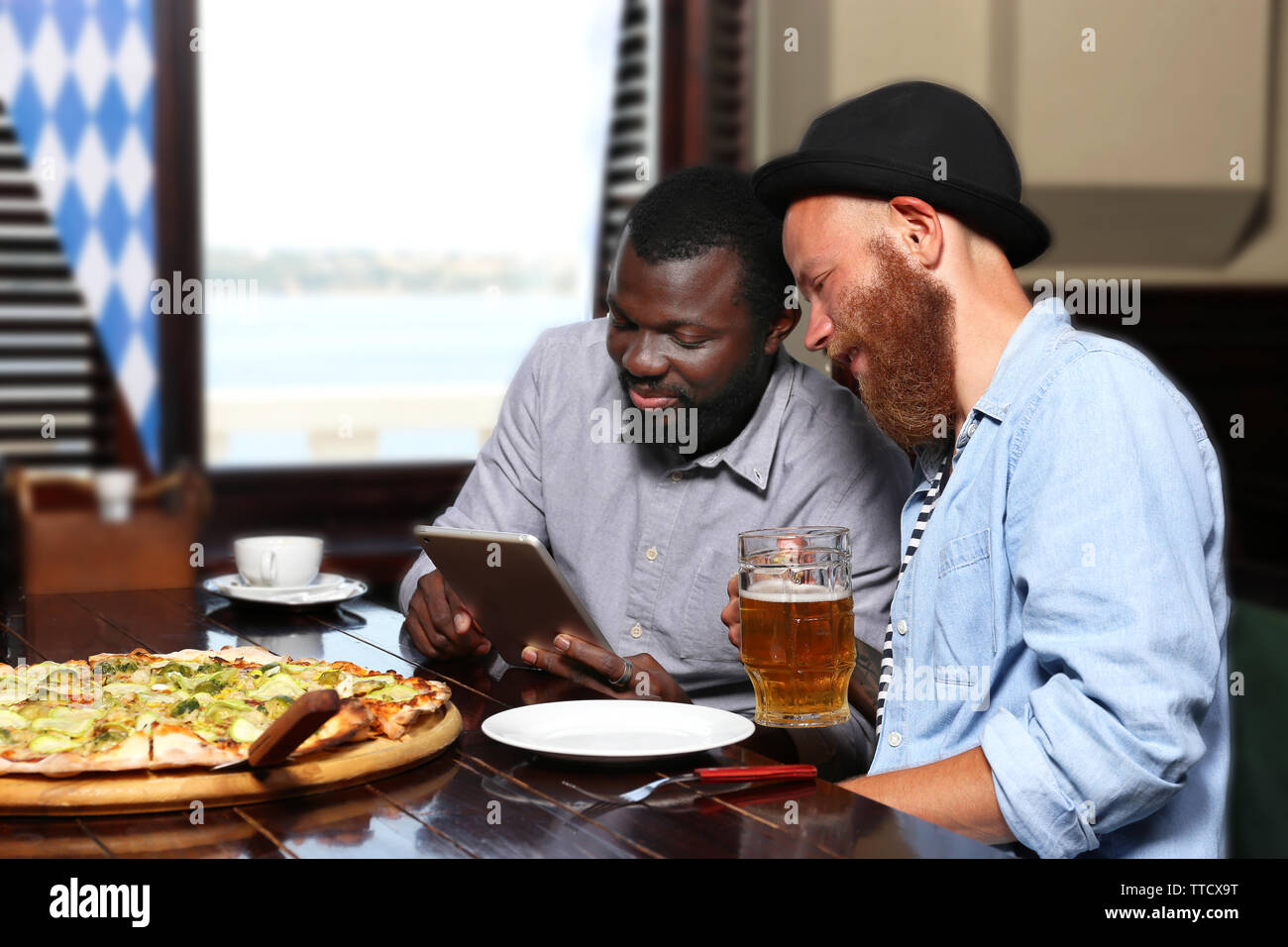 Young men drinking beer and talking in cafe Stock Photo - Alamy