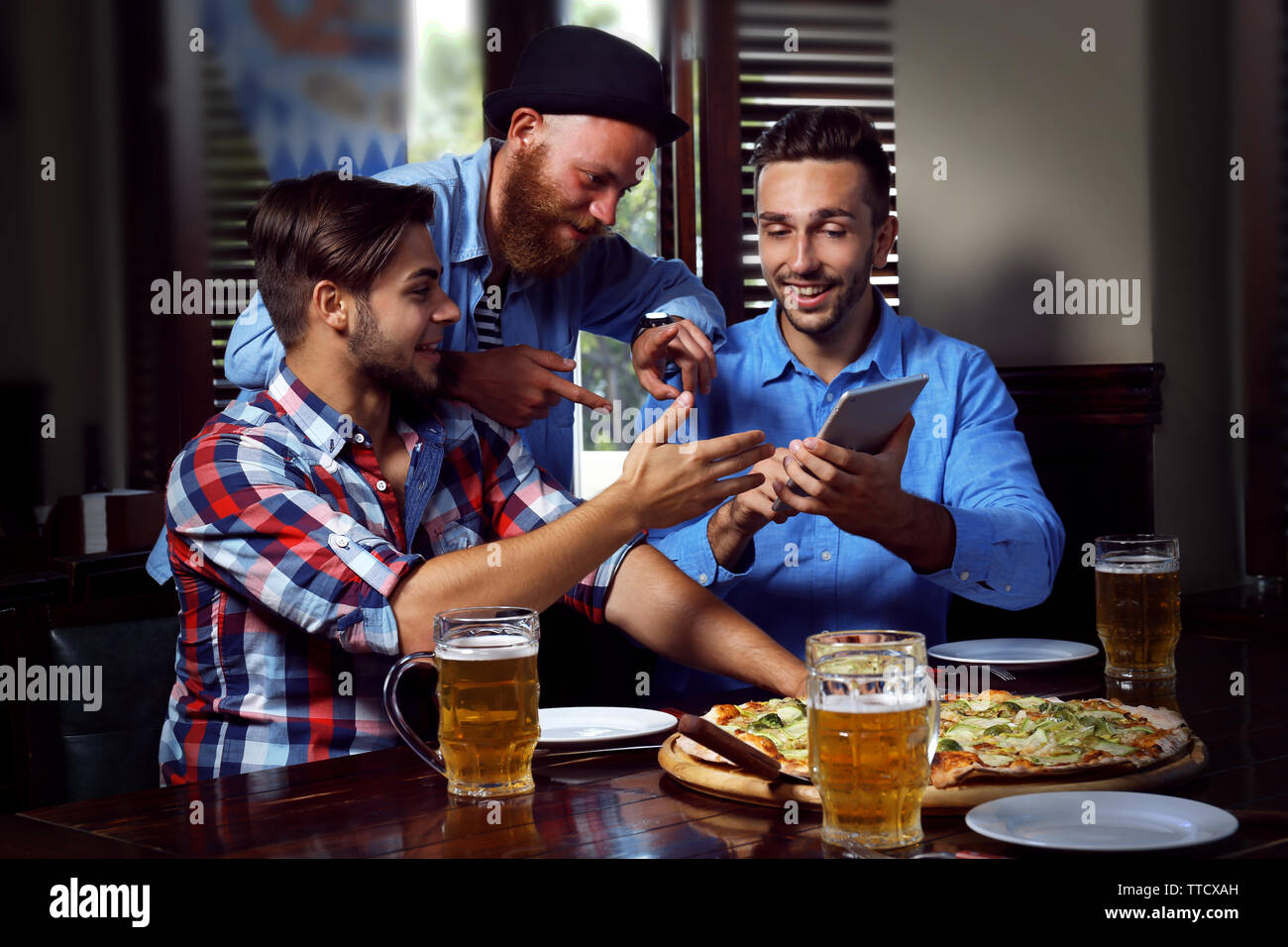 Young men drinking beer and talking in cafe Stock Photo - Alamy