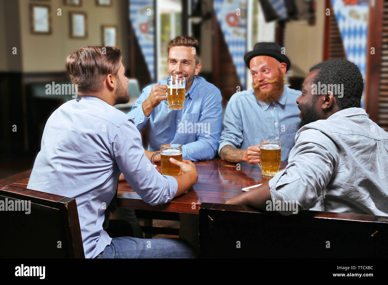 Young men drinking beer and talking in cafe Stock Photo - Alamy