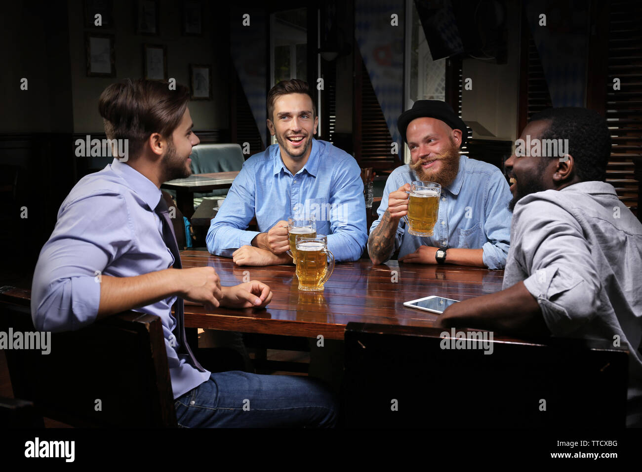 Young men drinking beer and talking in cafe Stock Photo - Alamy