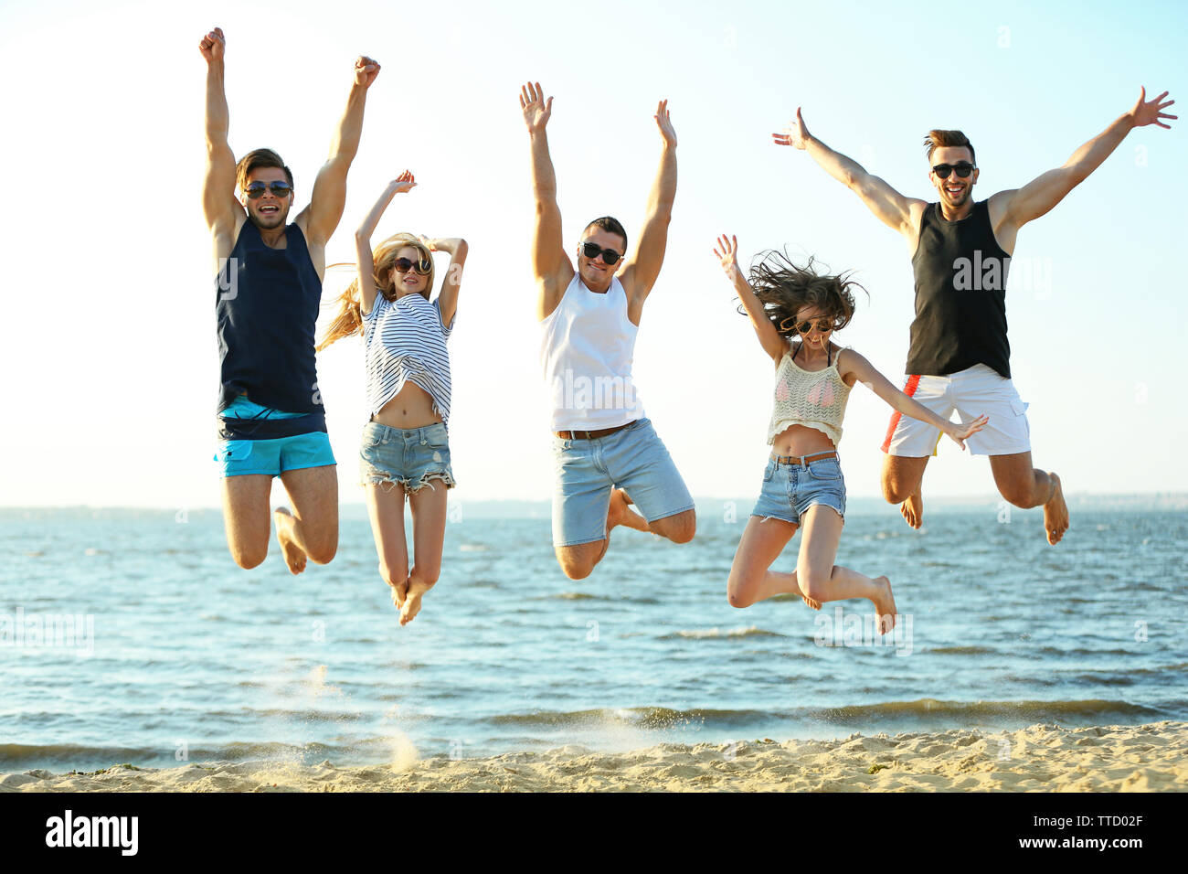 Happy friends jumping at the beach, outdoors Stock Photo - Alamy