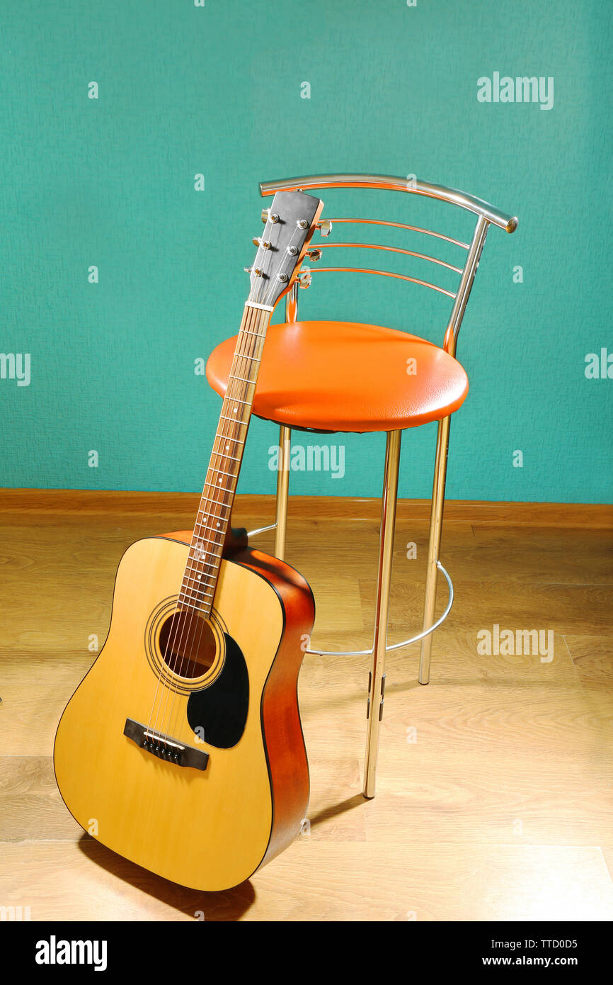 Guitar with bar stool on the floor against blue background in the ...