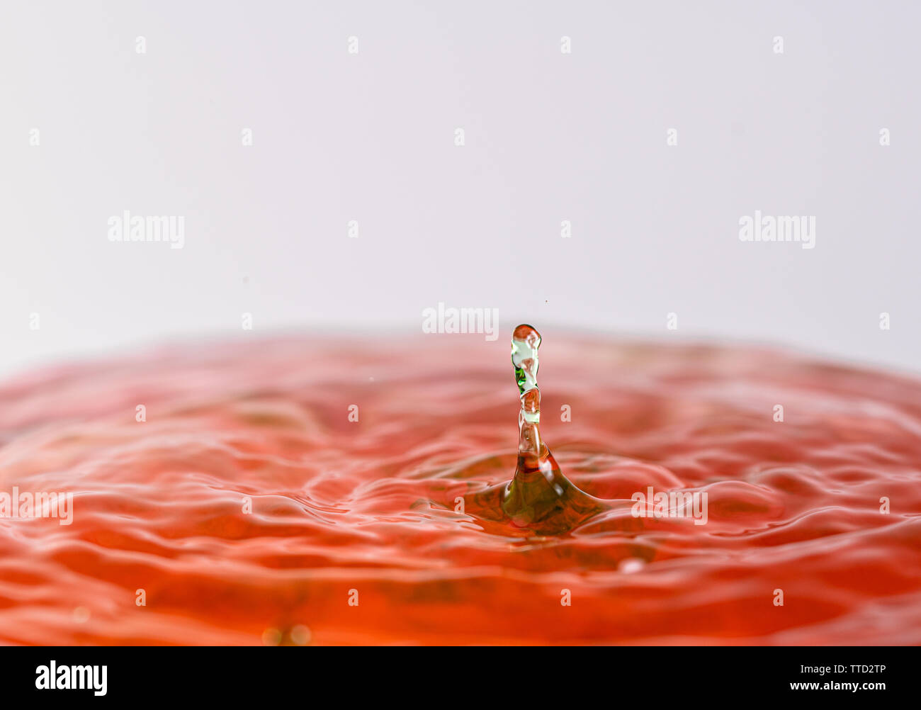 Close up macro photography of a red and green water drop splashing into ...