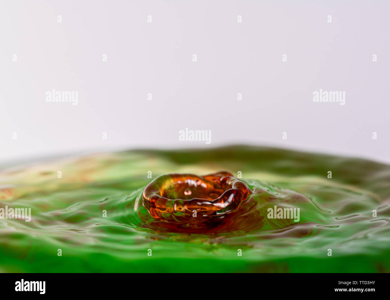 Close up macro photography of a red and green water drop splashing into ...