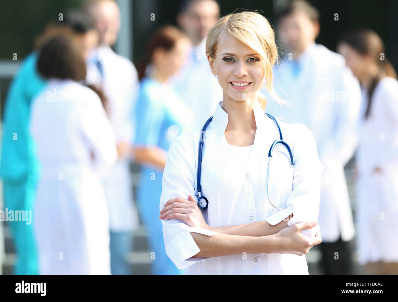 Beautiful smart woman doctor standing against blurred group of medics ...