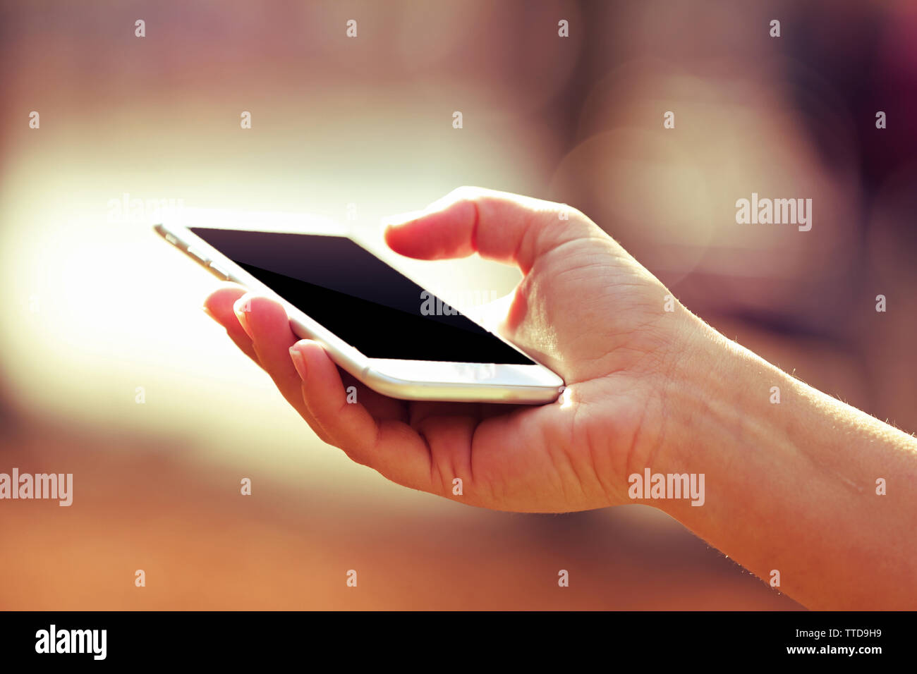 Hand holding smart phone on bright background Stock Photo - Alamy