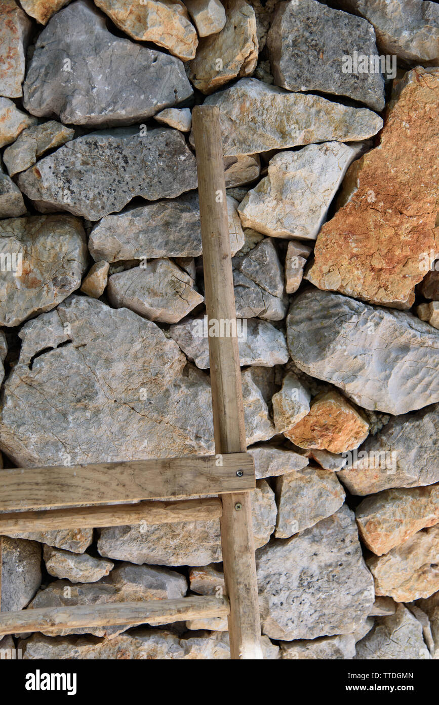 a detail of wooden ladders leaning against the old stone wall, abstract ...