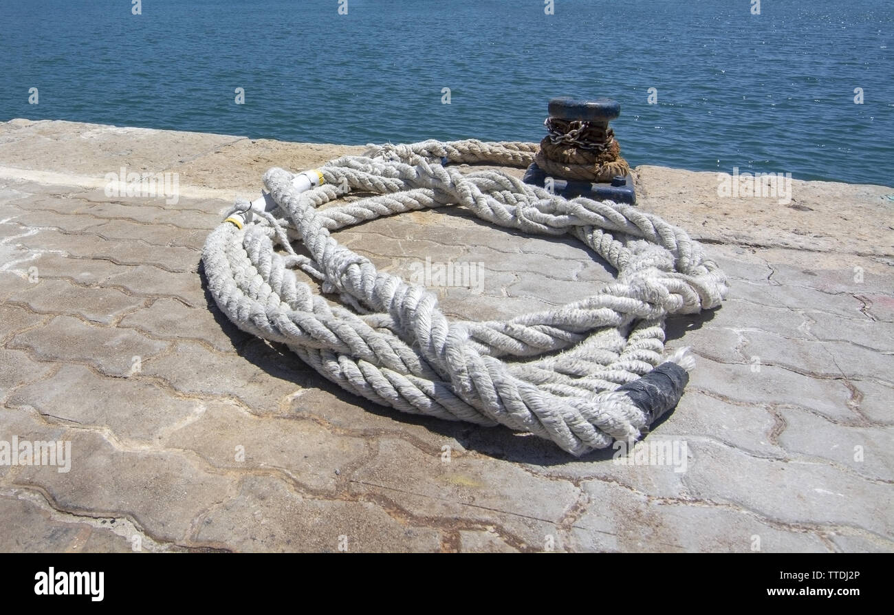 Thick white mooring rope closeup on empty mooring place on a sunny day ...
