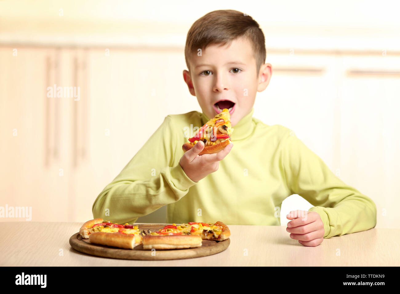 Little boy eating pizza at home Stock Photo - Alamy
