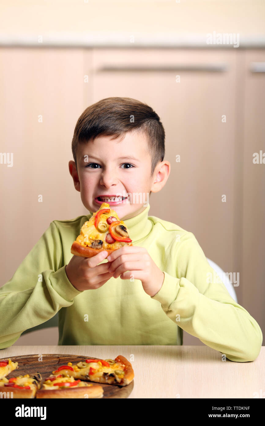 Little boy eating pizza at home Stock Photo - Alamy