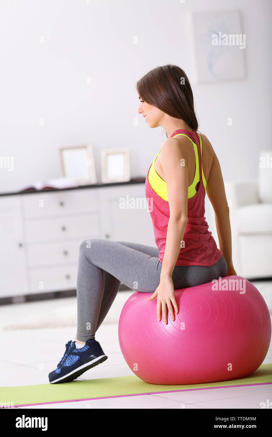 Beautiful young girl doing exercises with fit ball at home Stock Photo ...