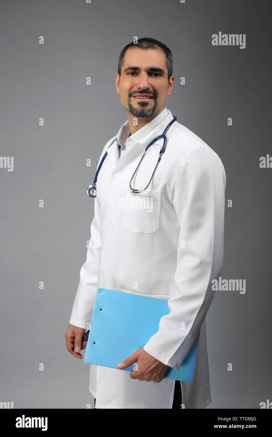 Portrait of a doctor with prescription board in hands on grey ...
