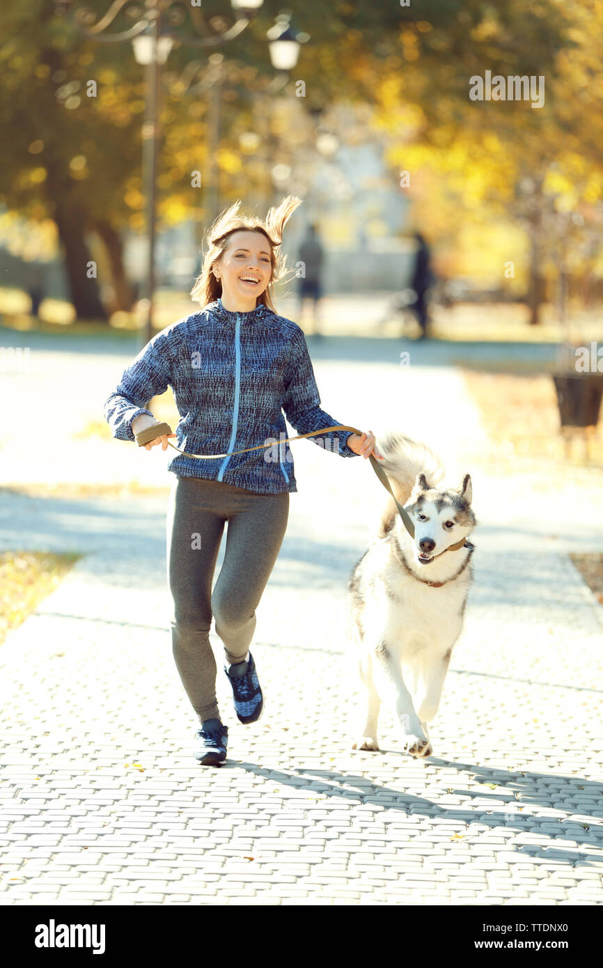 Happy young woman jogging with her dog in park Stock Photo - Alamy