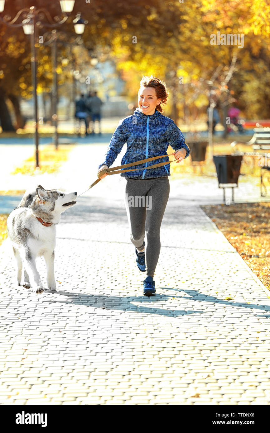 Happy young woman jogging with her dog in park Stock Photo - Alamy