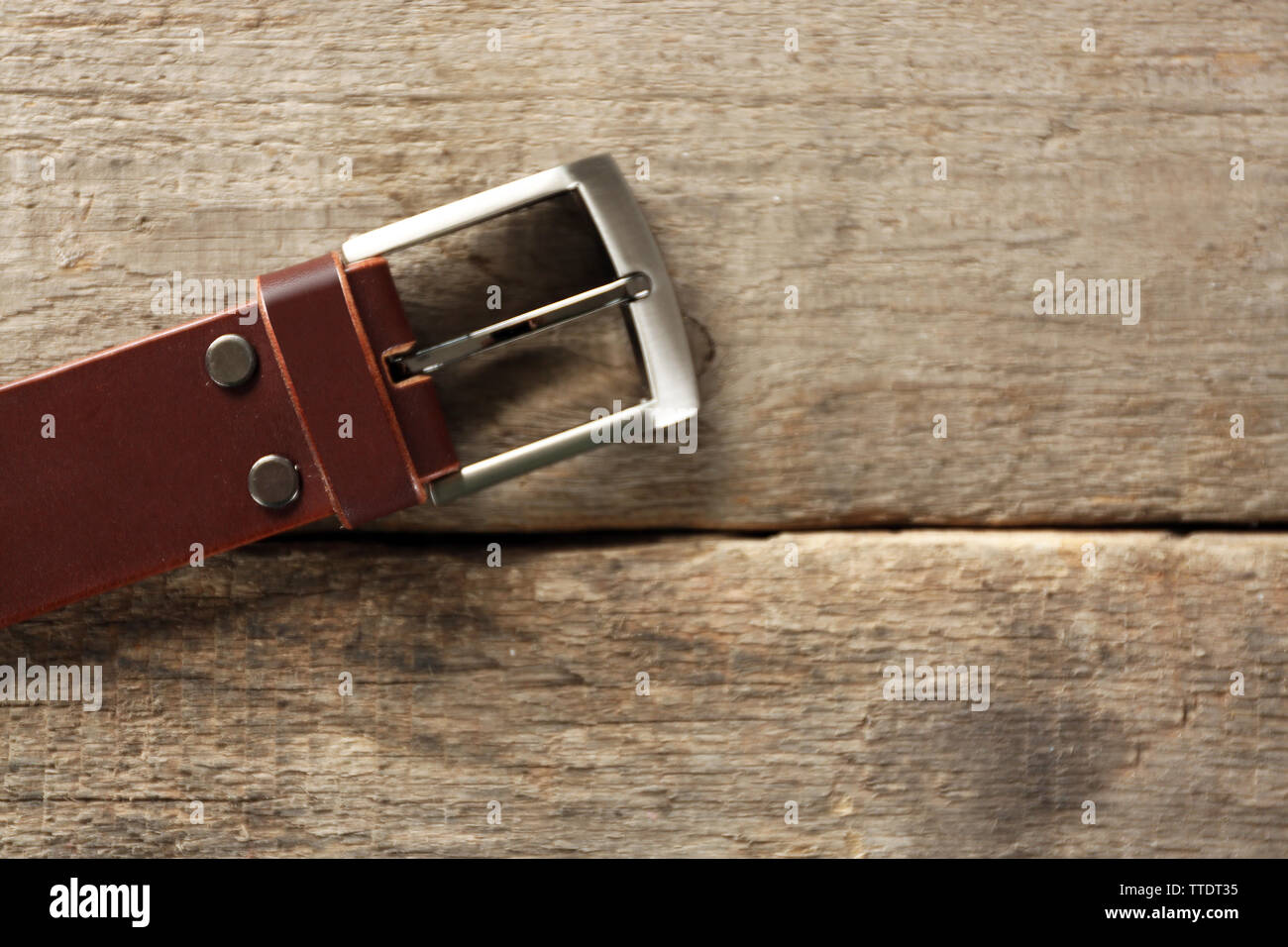 Leather belt with buckle on wooden background Stock Photo - Alamy