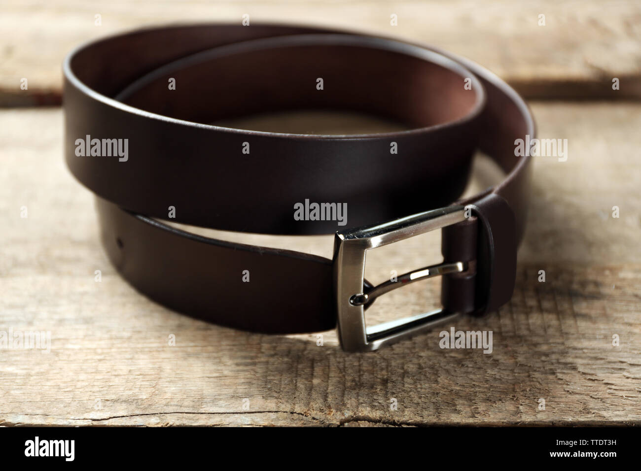 Leather belt with buckle on wooden background Stock Photo - Alamy