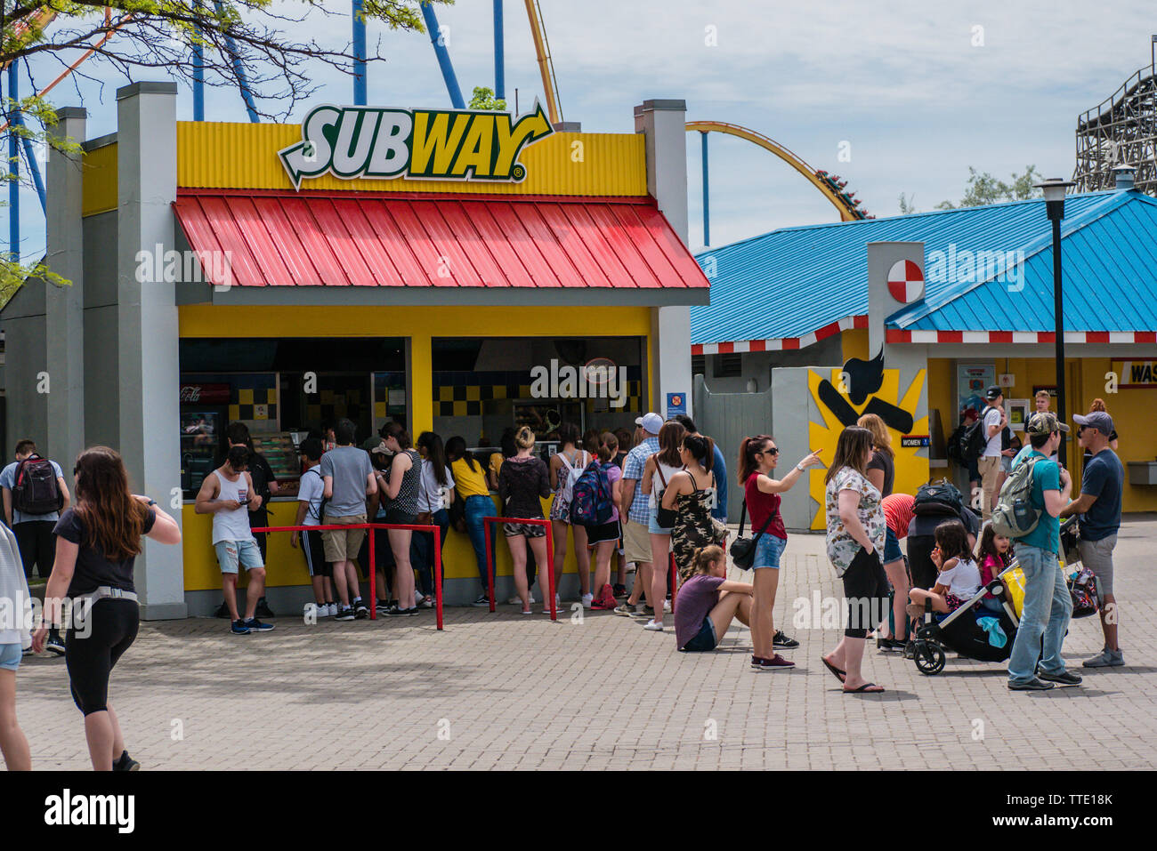 people line up in front of a subway sandwich restaurant in the summer ...