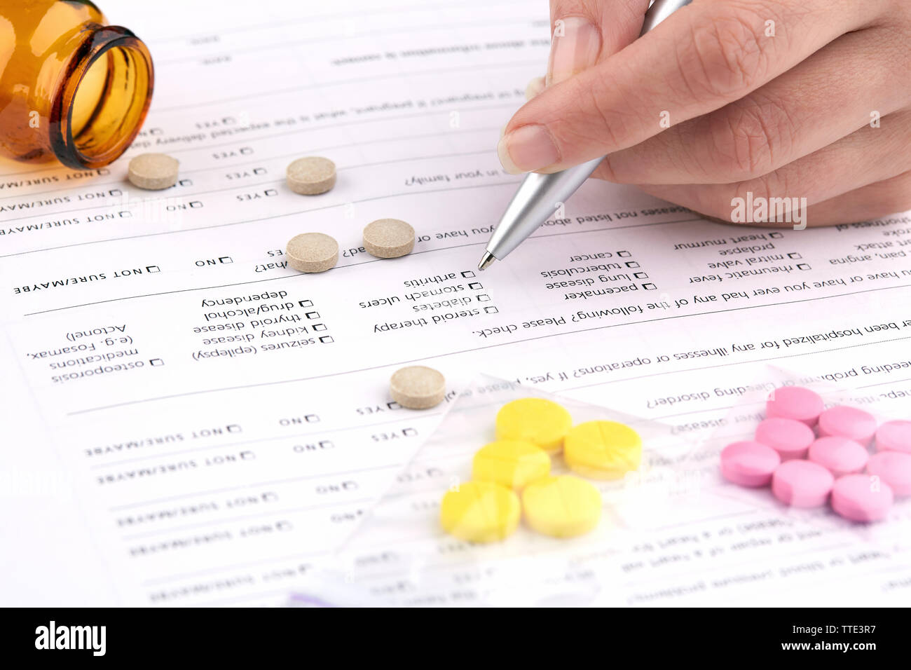 Colorful pills, brown vial and hand writing on medical questionnaire ...