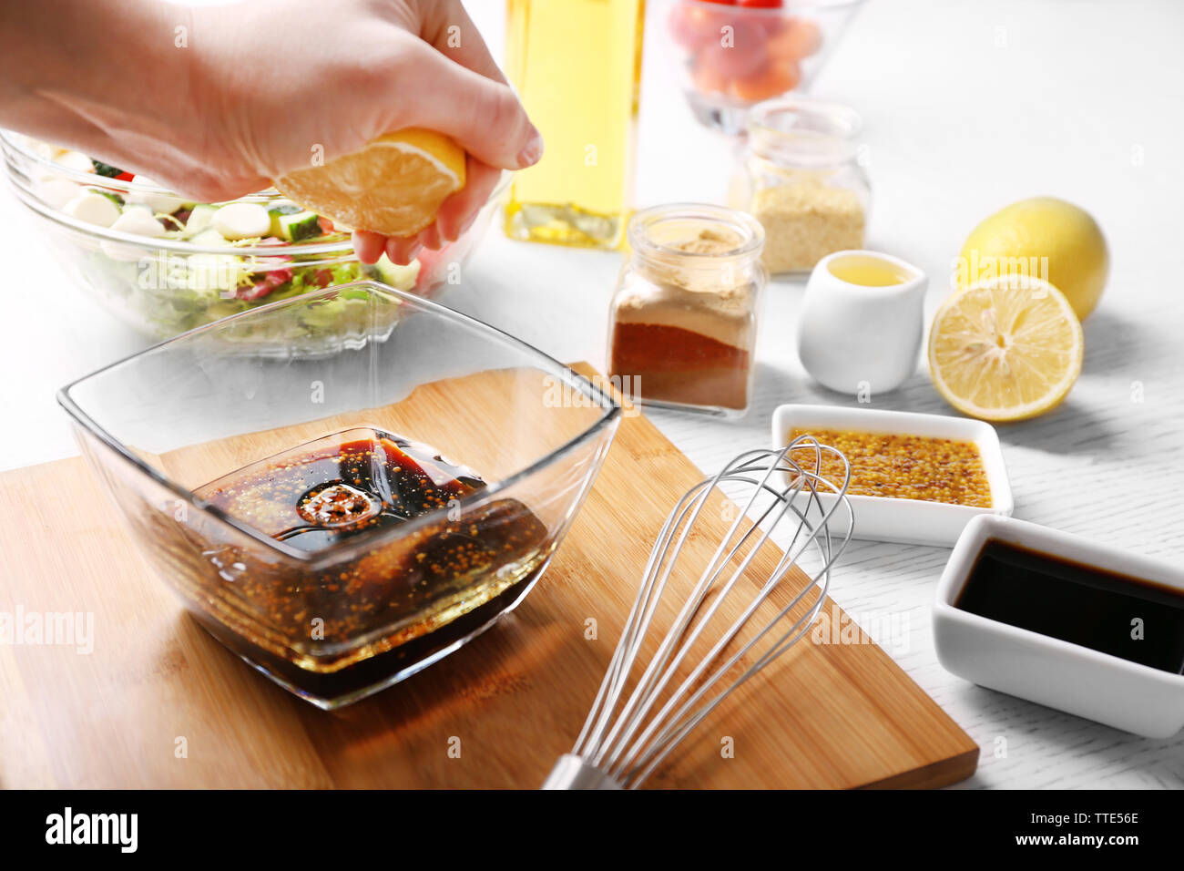Process of preparing sauce for salad, at kitchen. Female hands squeeze ...