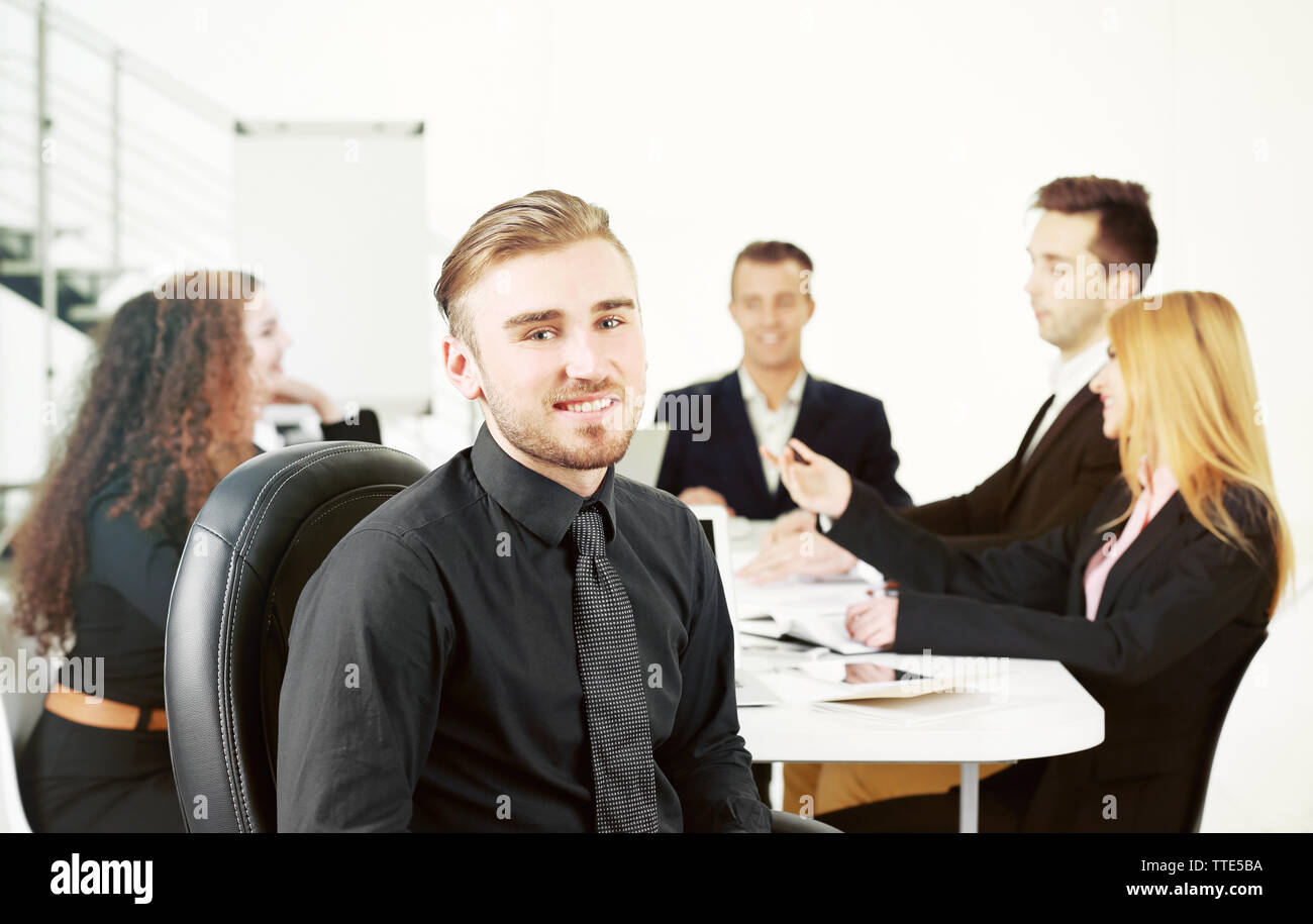 Photo of a young business man with his staff at the meeting in a ...