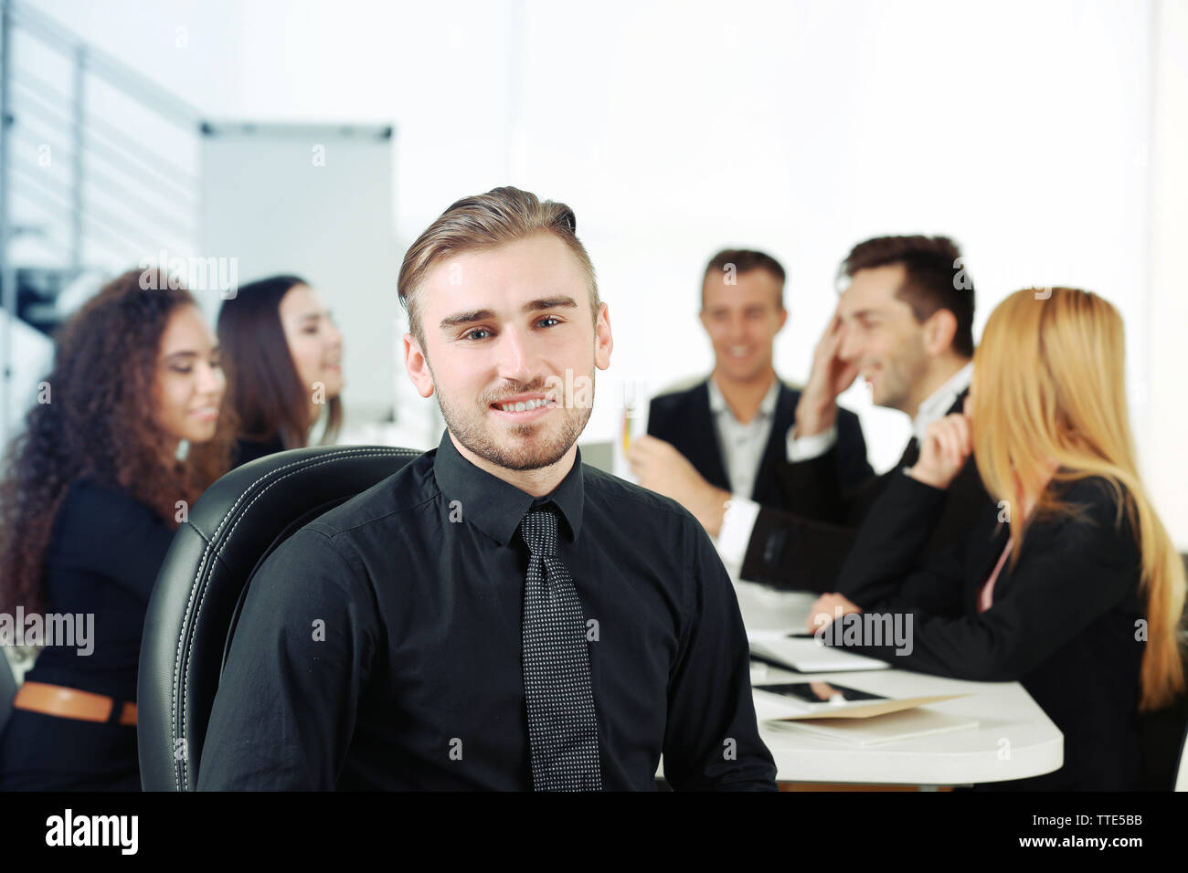 Photo of a young business man with his staff at the meeting in a ...