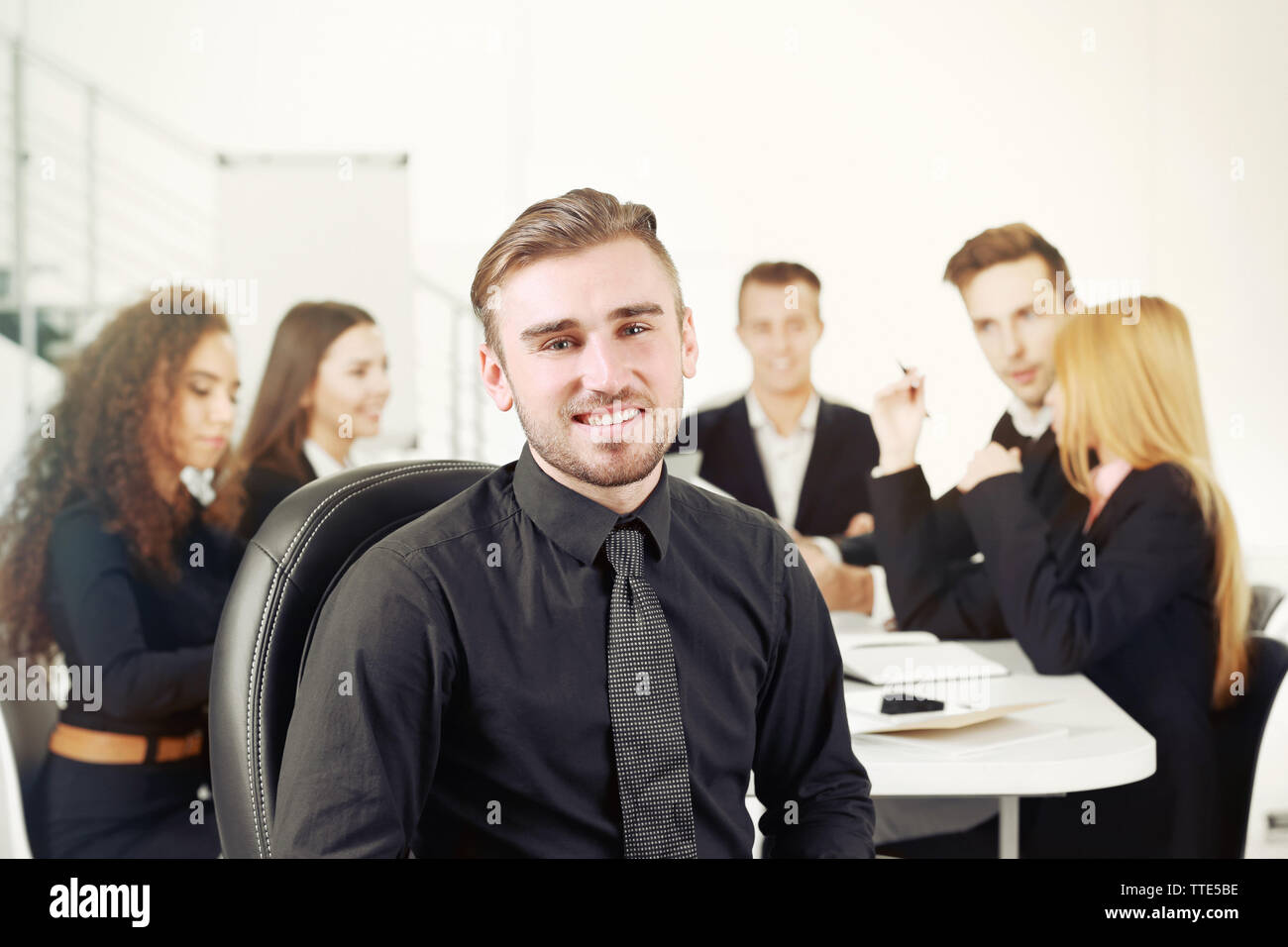 Photo of a young business man with his staff at the meeting in a ...