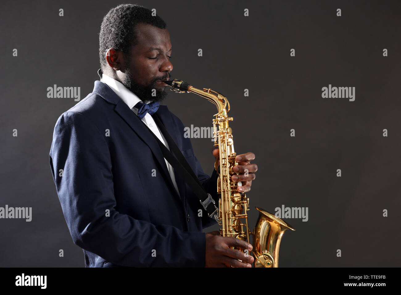 African American jazz musician playing the saxophone on grey background ...