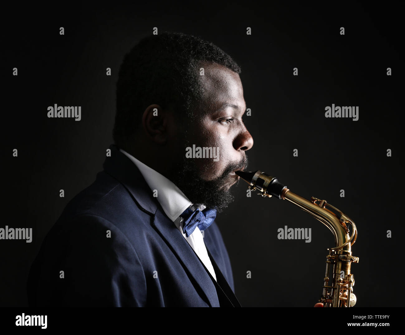 African American jazz musician playing the saxophone on grey background ...