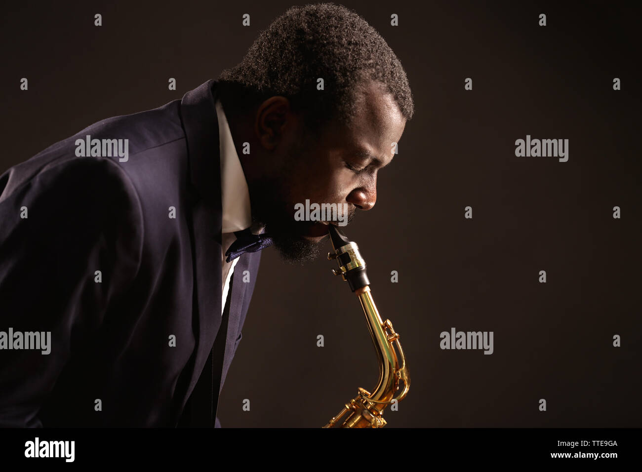 African American jazz musician playing the saxophone on grey background ...