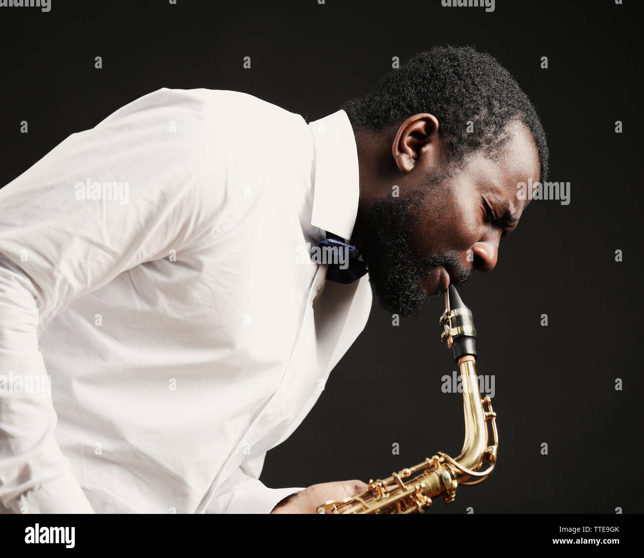 African American jazz musician playing the saxophone on grey background ...