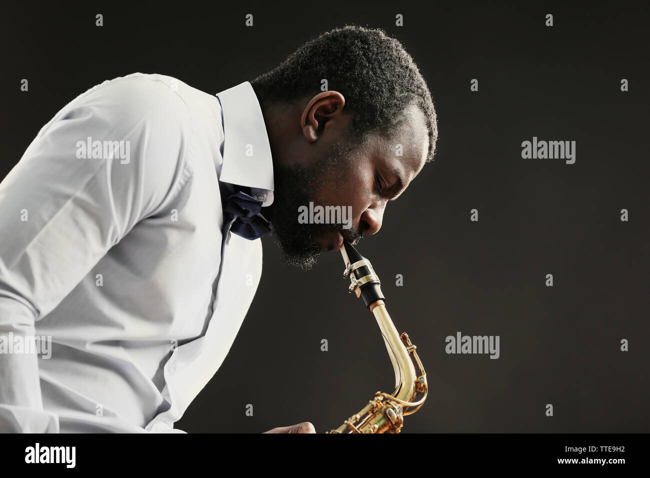 African American jazz musician playing the saxophone on grey background ...